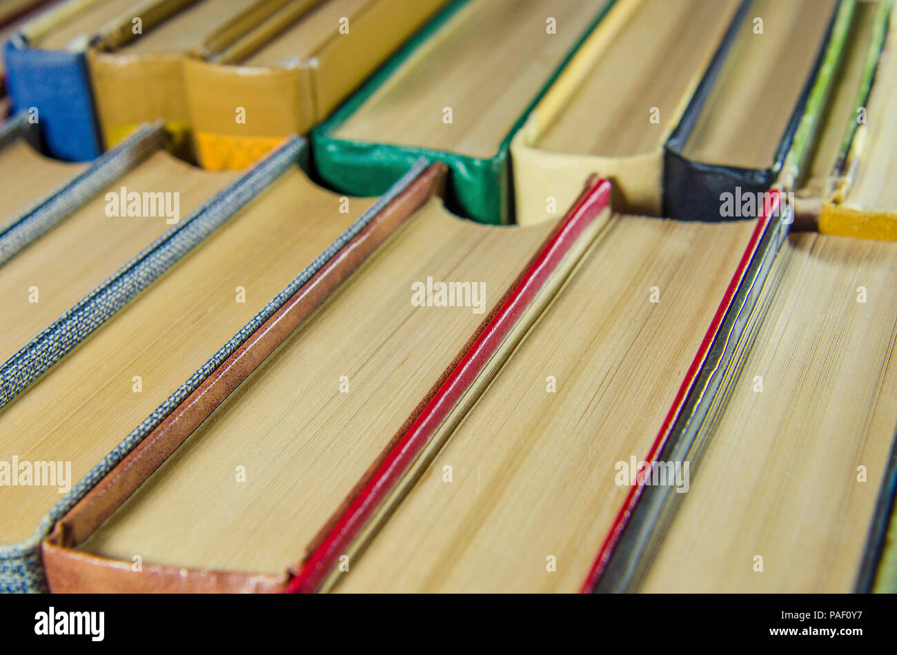 a stack of colorful books on the shelf in a library or a room close-up ...