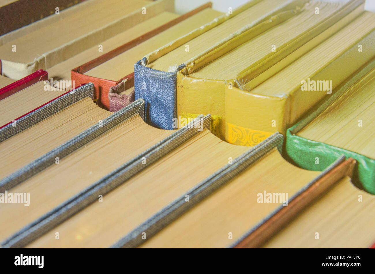 a stack of colorful books on the shelf in a library or a room close-up ...