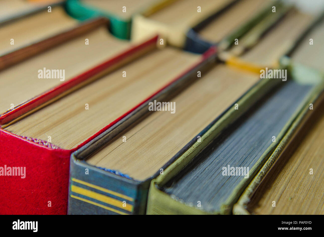 a stack of colorful books on the shelf in a library or a room close-up ...