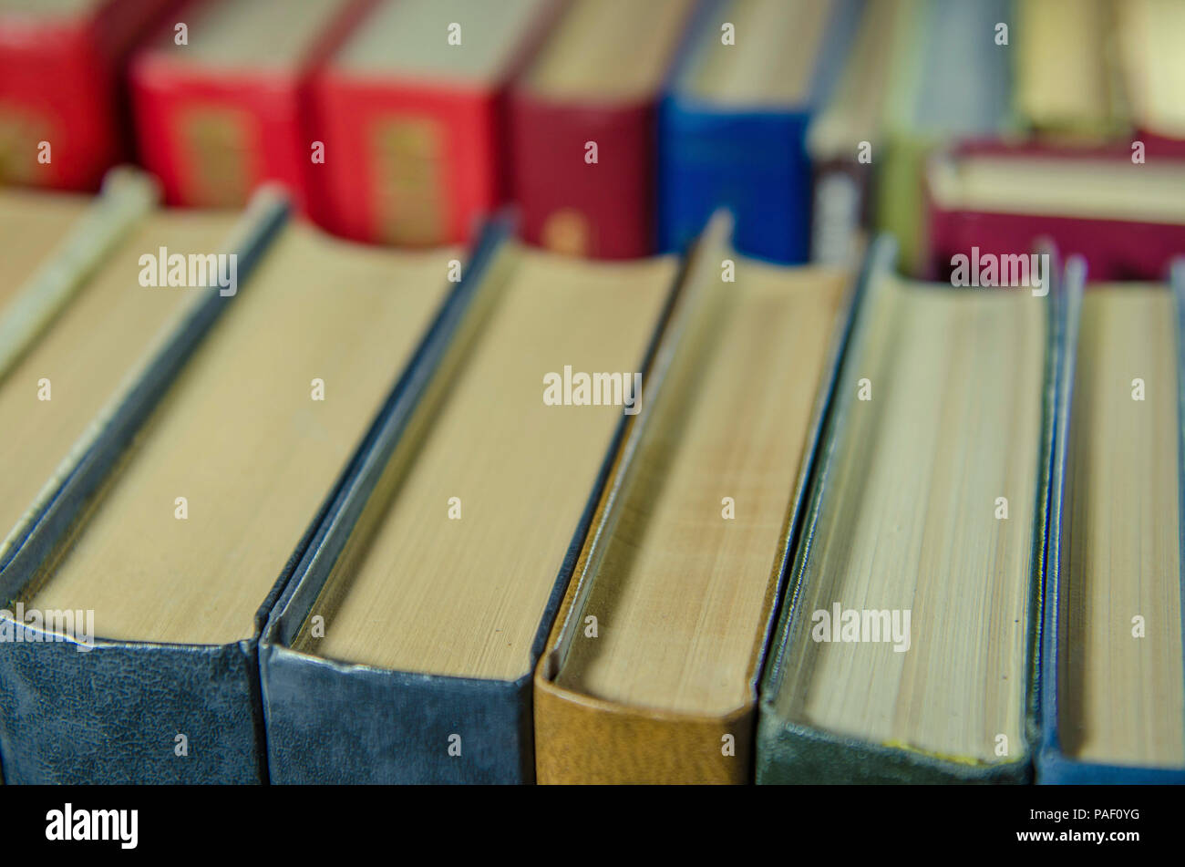 a stack of colorful books on the shelf in a library or a room close-up ...