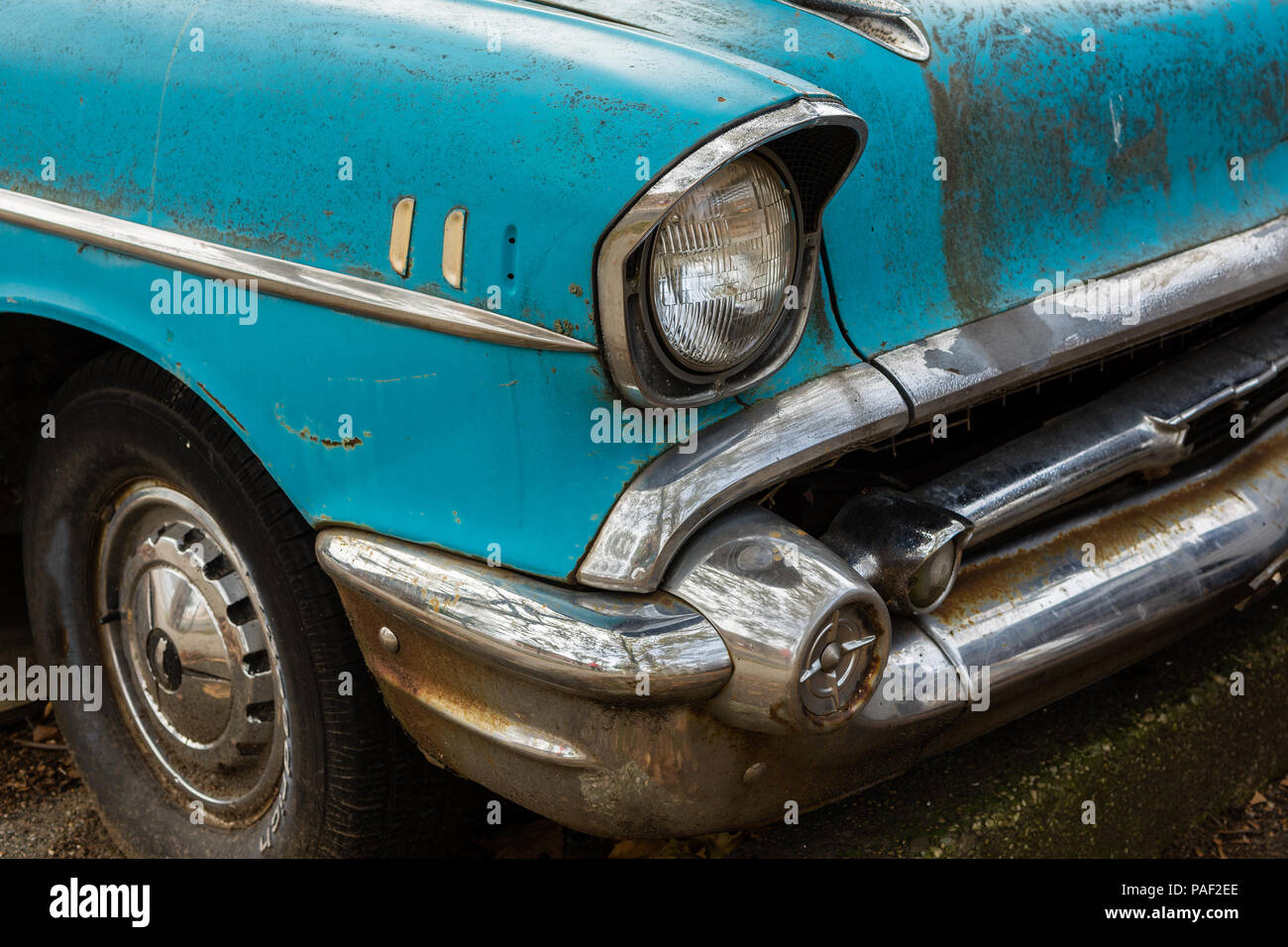 Fragment of the front of the old blue car with a slightly rusty bumper ...