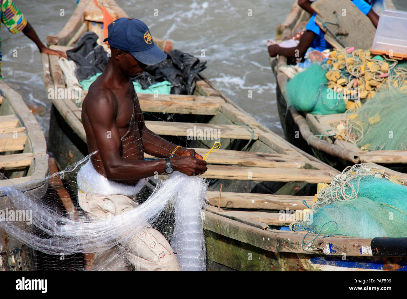 African fisherman maintaining a fishing net between wooden dugout ...