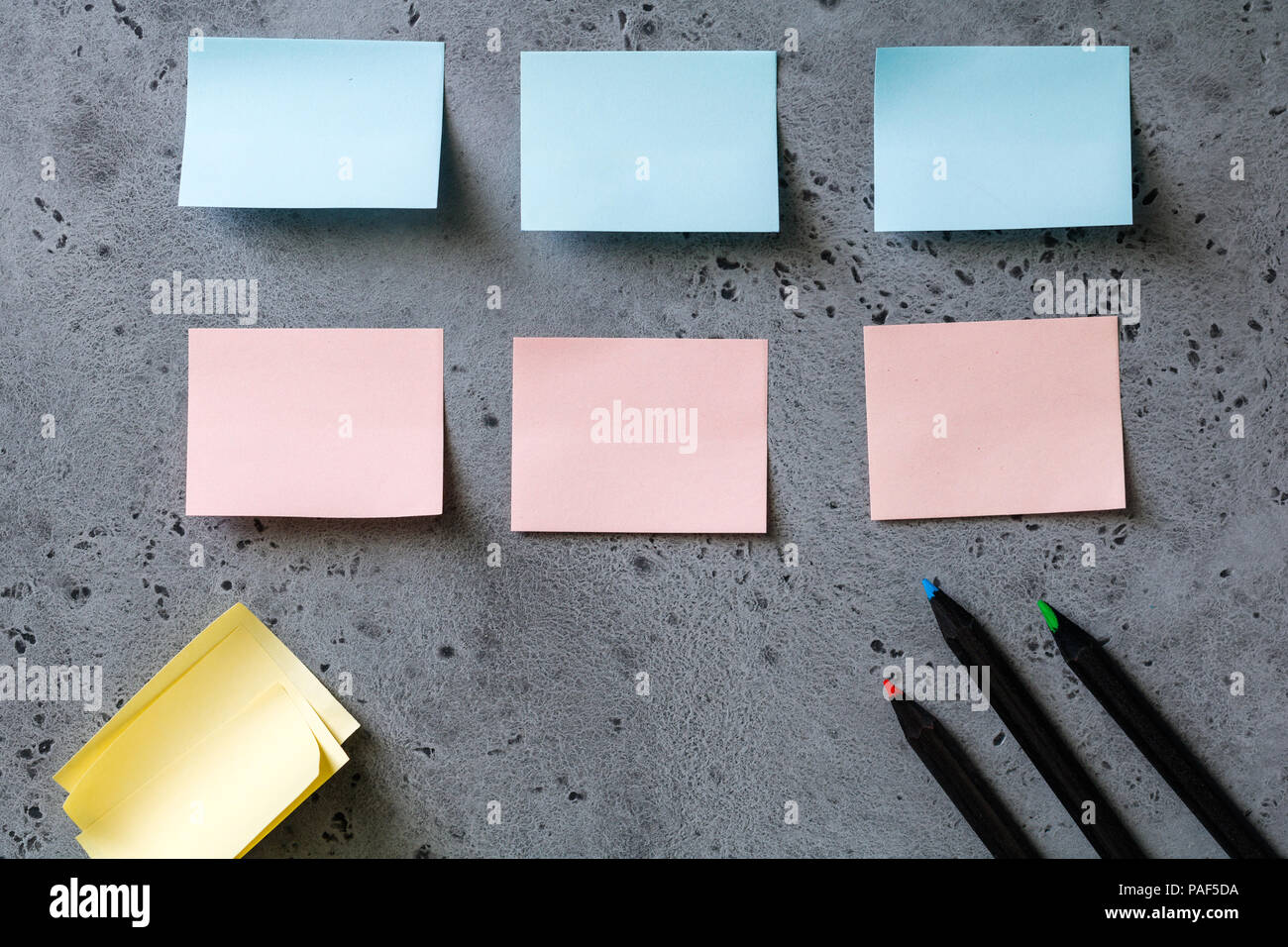Colorful empty sticky notes and pencils on a textured background. The ...