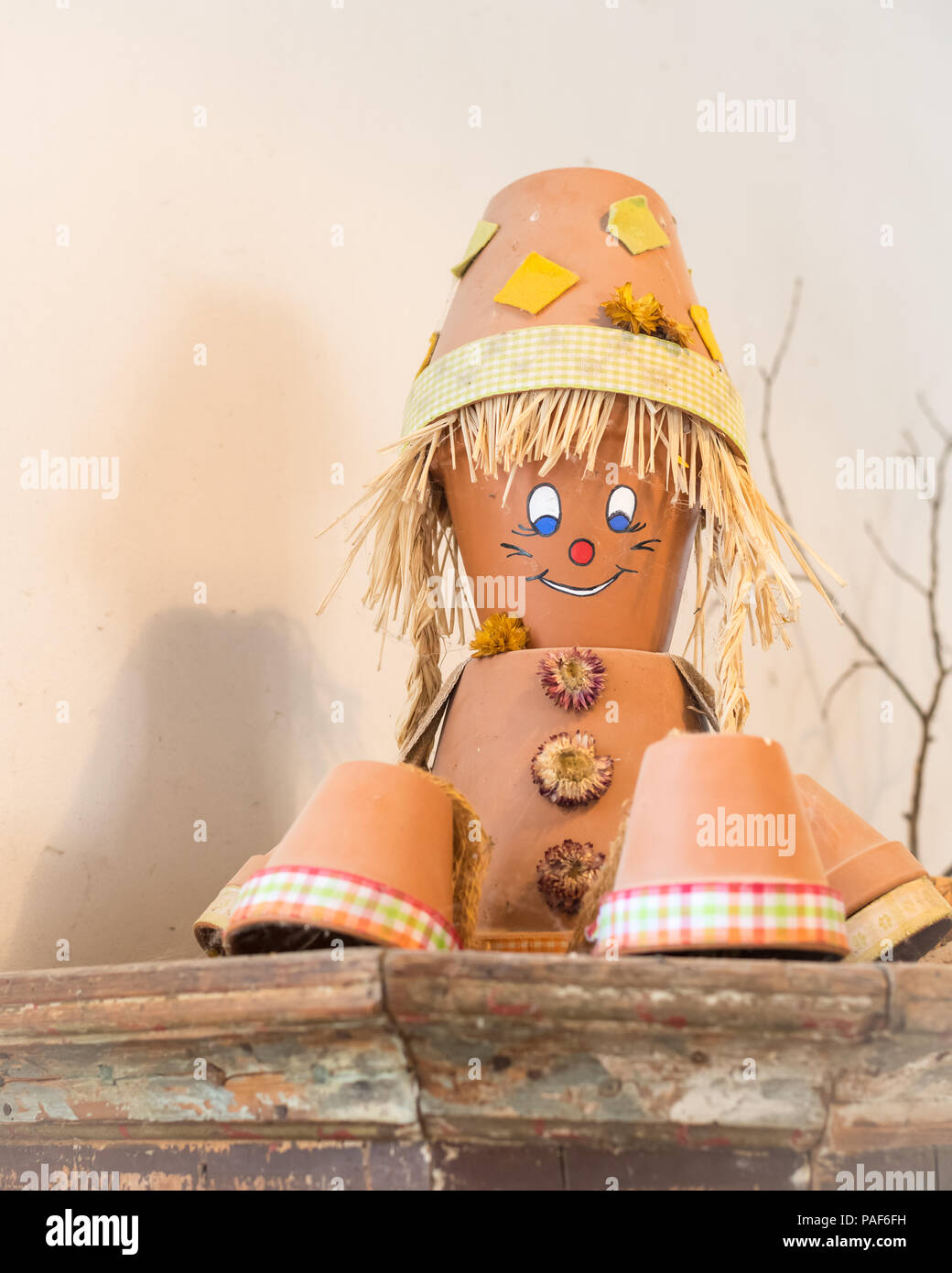 Puppet made of flowerpots and straw sitting on a board, blue eyes ...