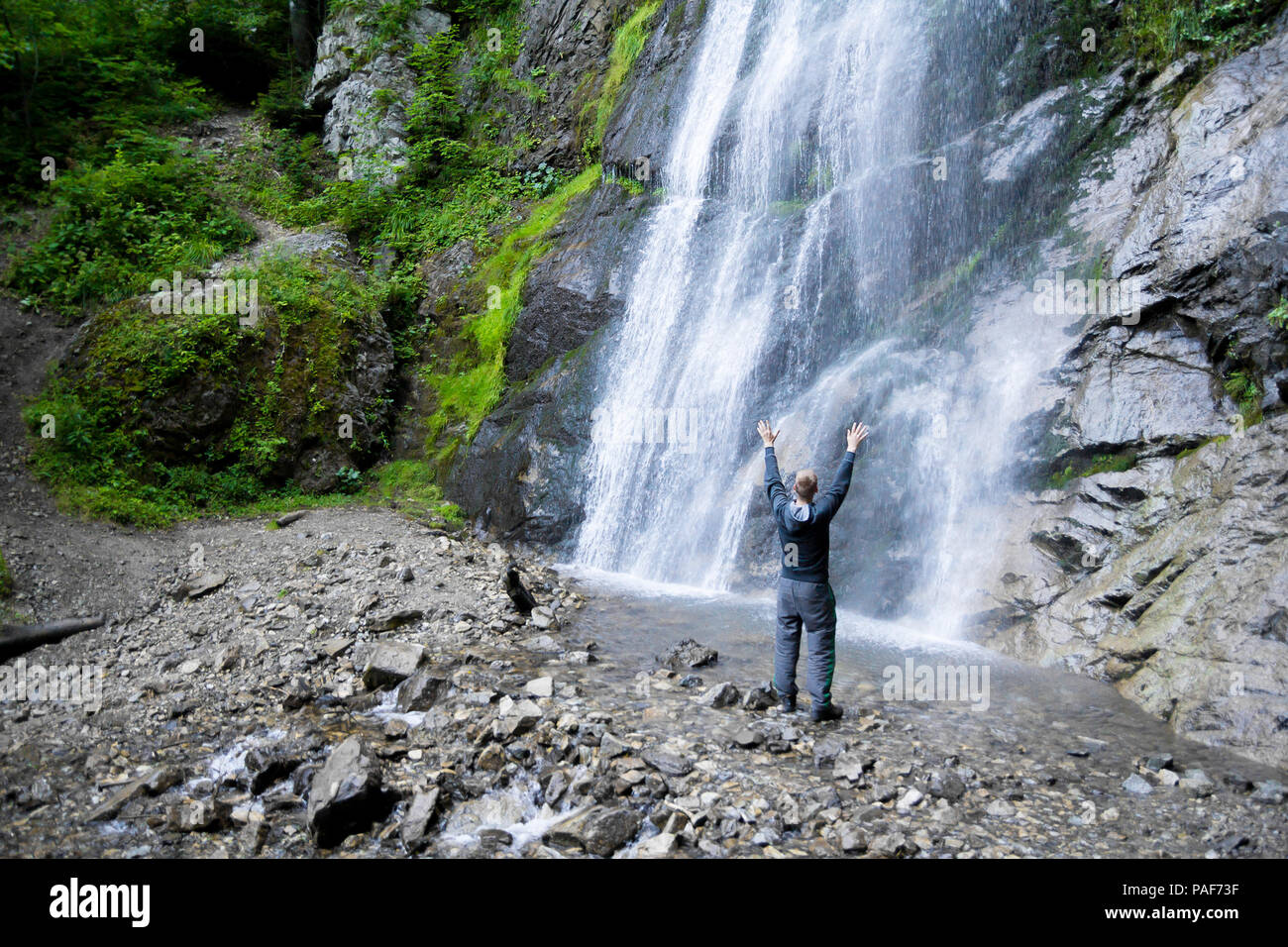 man standing by waterfalls with arms outstretched in the air Stock ...