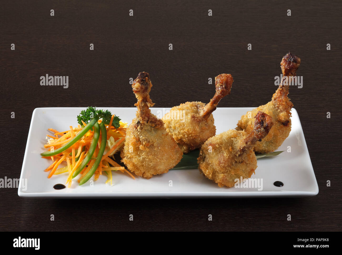 Fried chicken legs. White dish on wooden background Stock Photo - Alamy