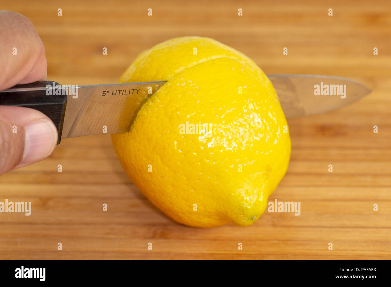 Lemon being sliced in half on a cutting board on a kitchen table Stock ...