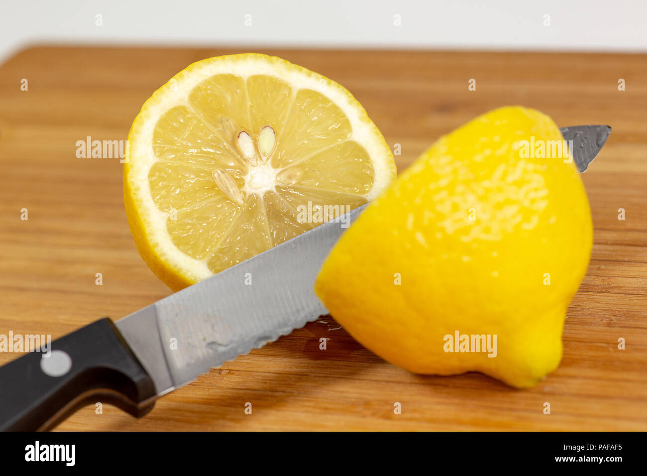 Lemon being sliced in half on a cutting board on a kitchen table Stock ...