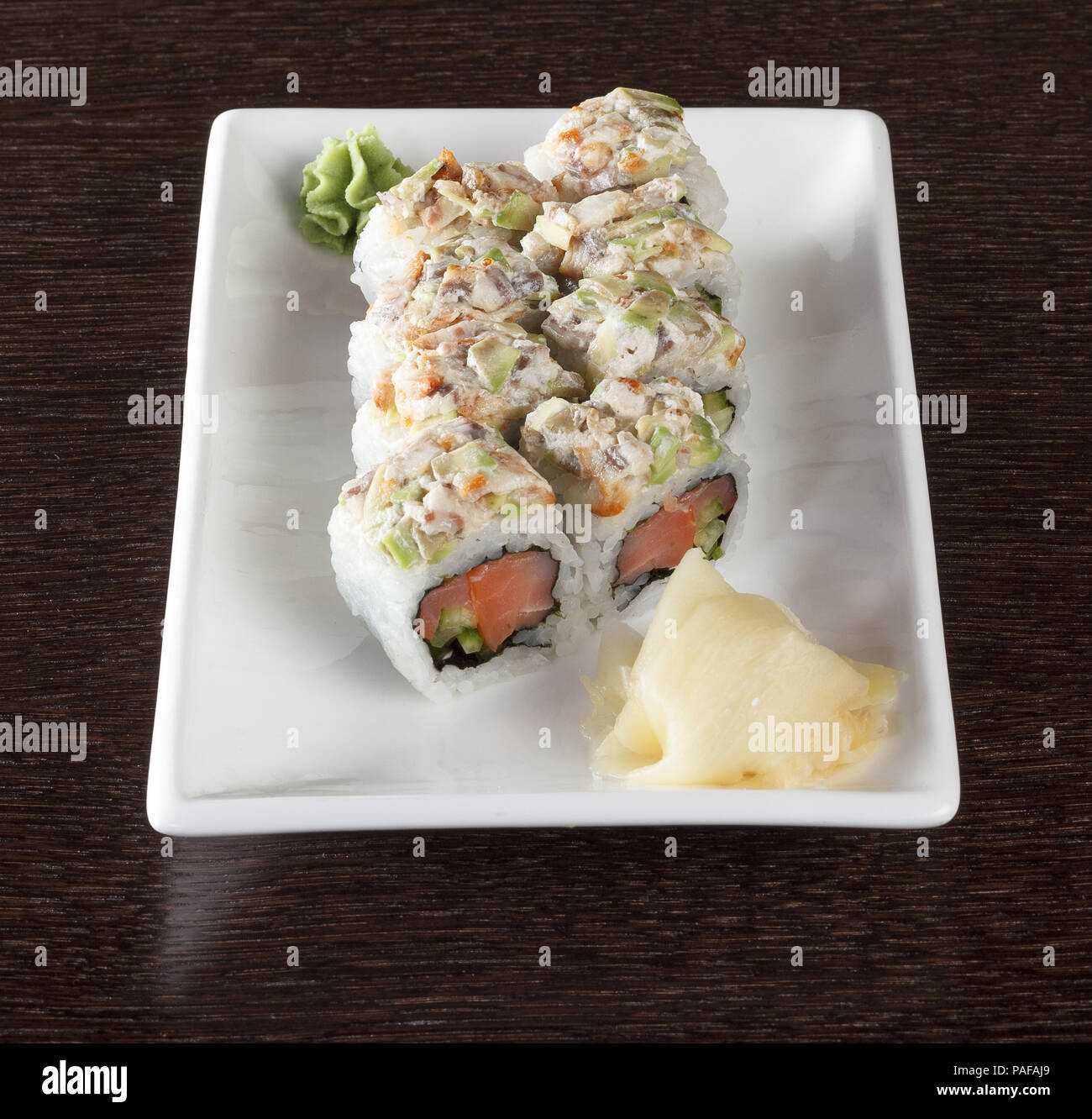 Sushi rolls with salmon and tuna on a plate on wooden table. Side view ...