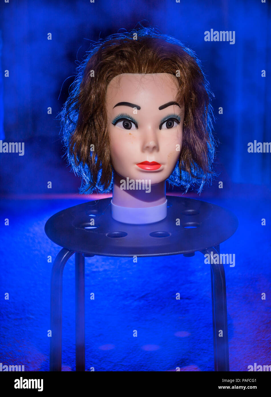 Scary backlit young female dummy head in blue light with misty ...