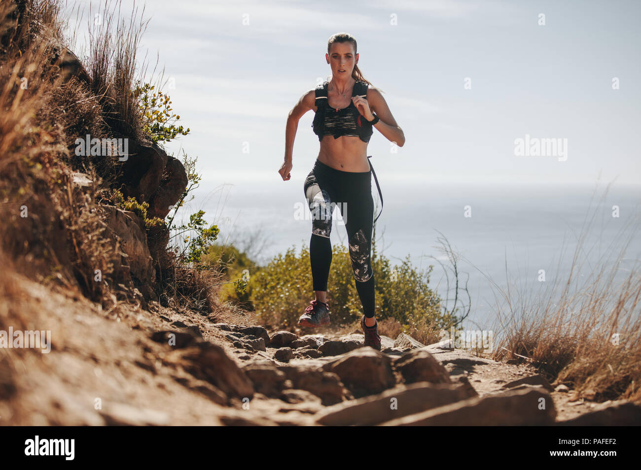 Full length of fitness woman running over rock trail on mountain. Fit ...