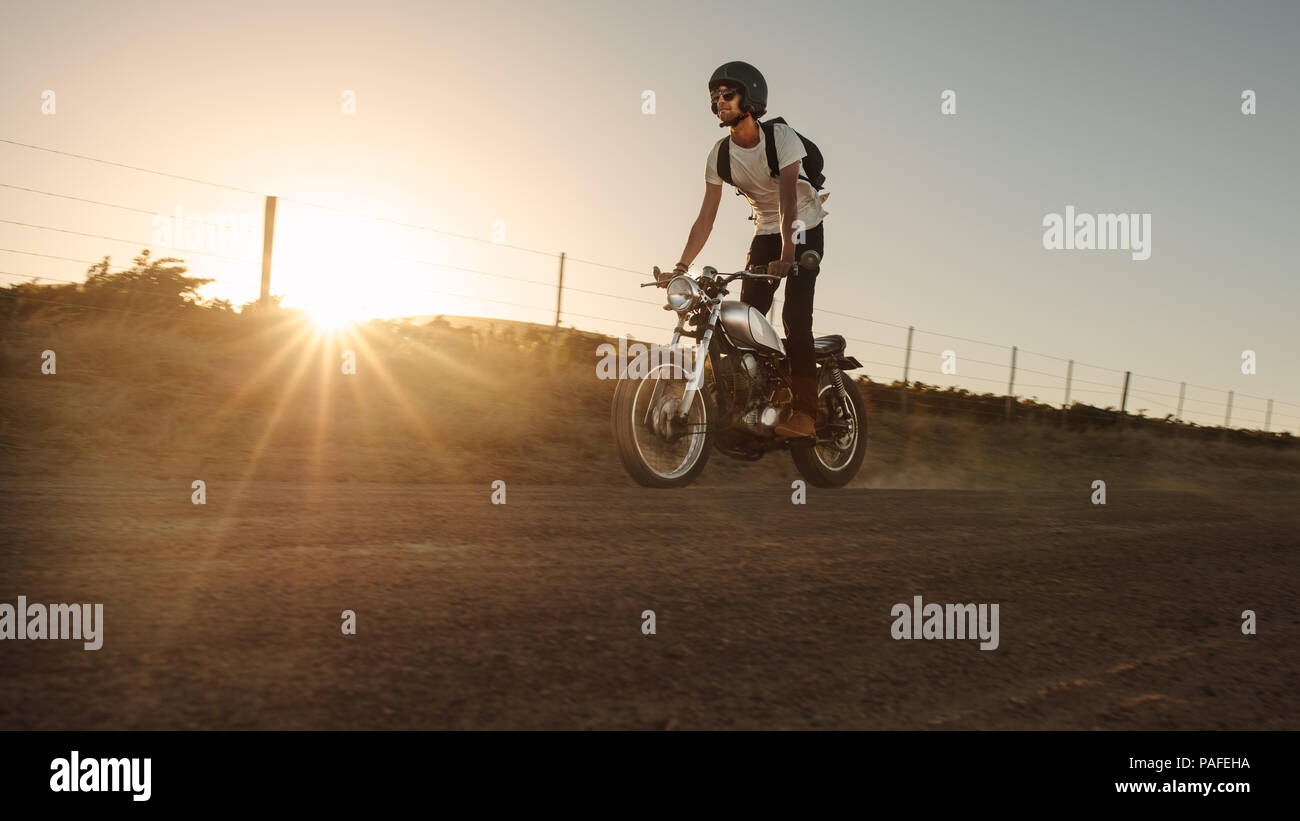 Biker standing on his bike while driving through country road. Young ...