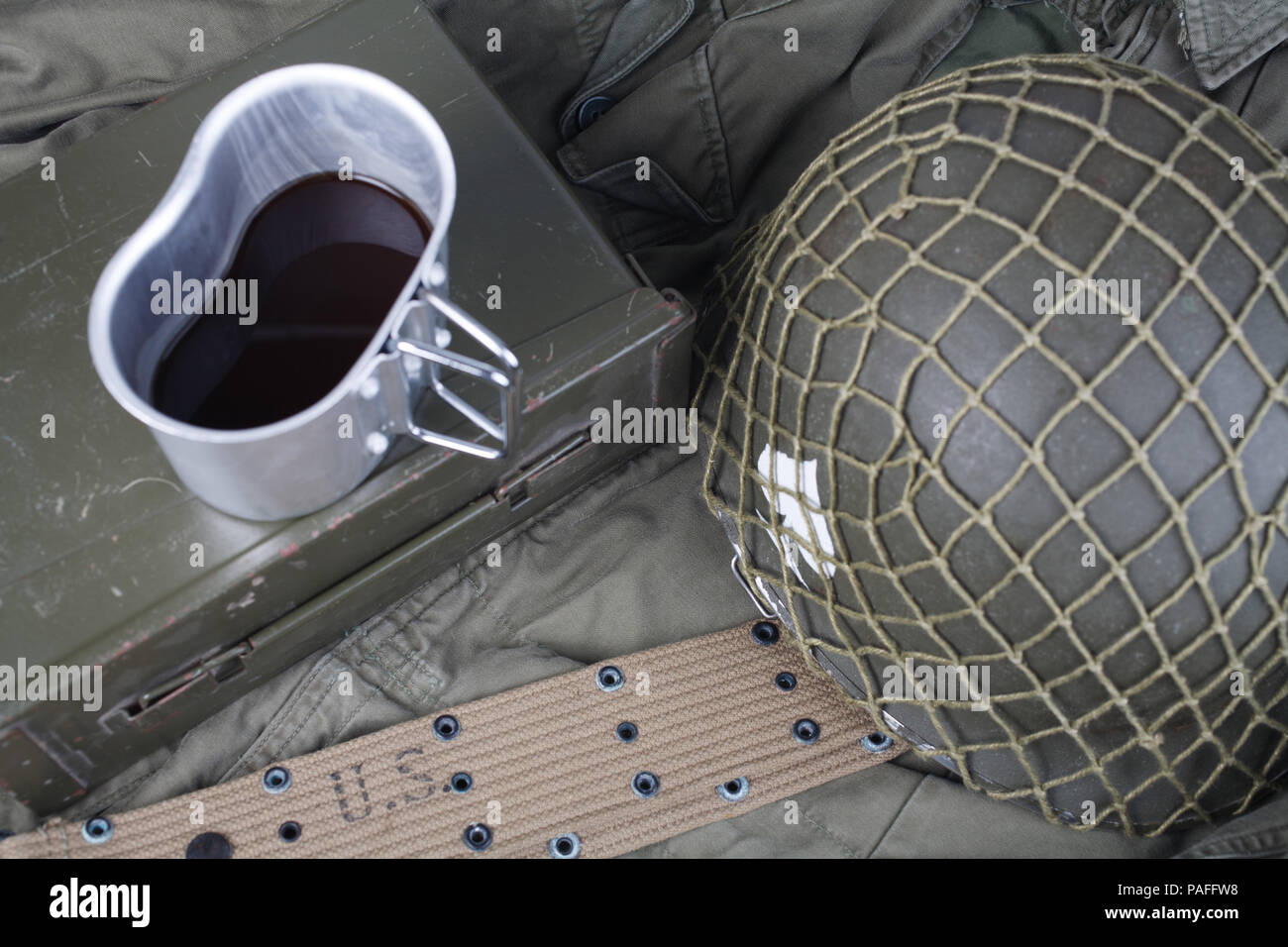 a cup of coffee with ww2 period us army military equipment on green ...