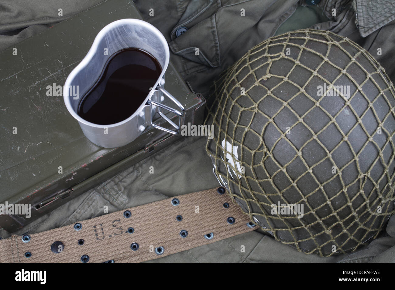 a cup of coffee with ww2 period us army military equipment on green ...