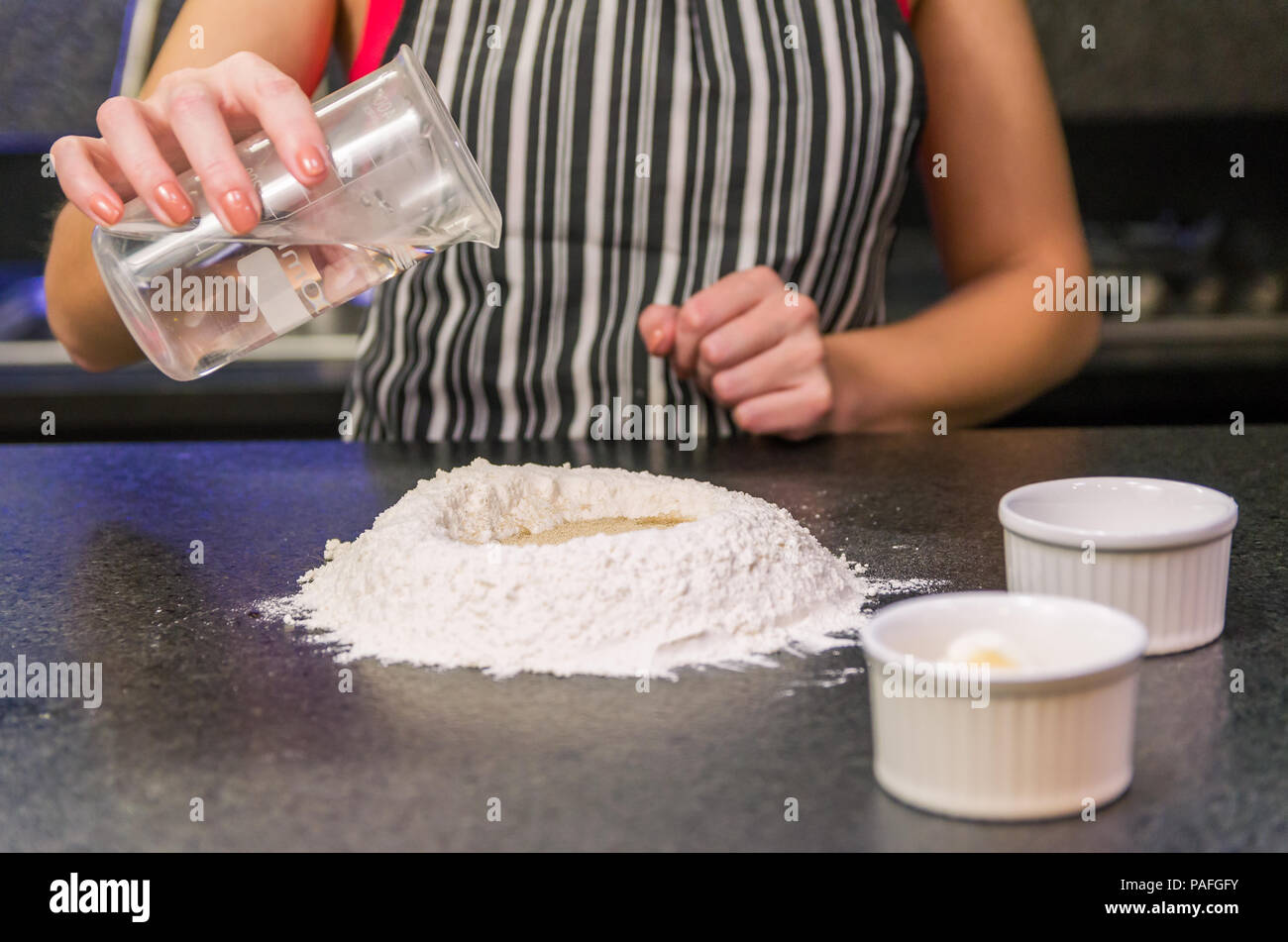 Woman preparing pizza dough on black granite table Stock Photo - Alamy