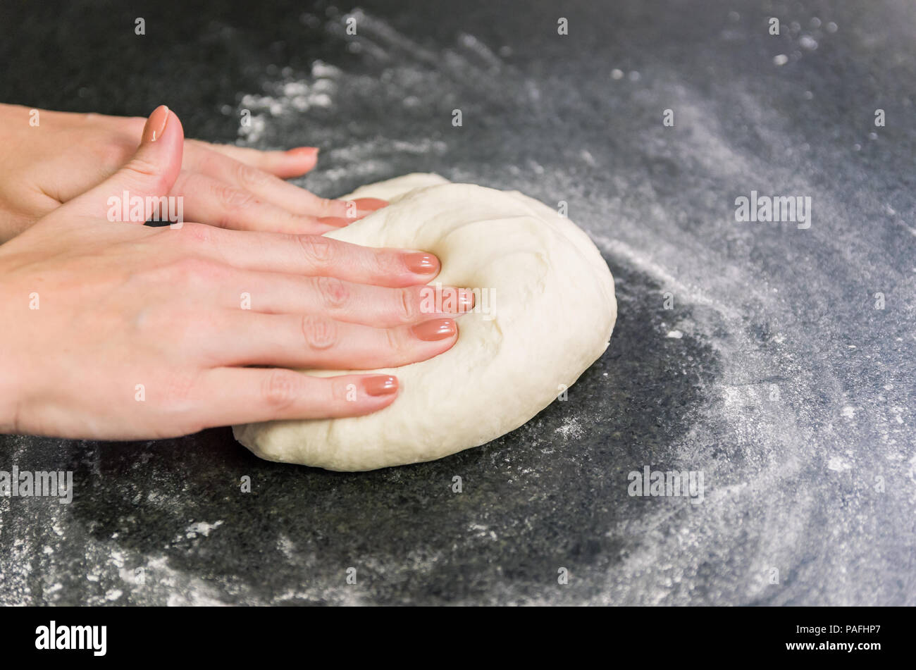 Woman preparing pizza dough on black granite table Stock Photo - Alamy