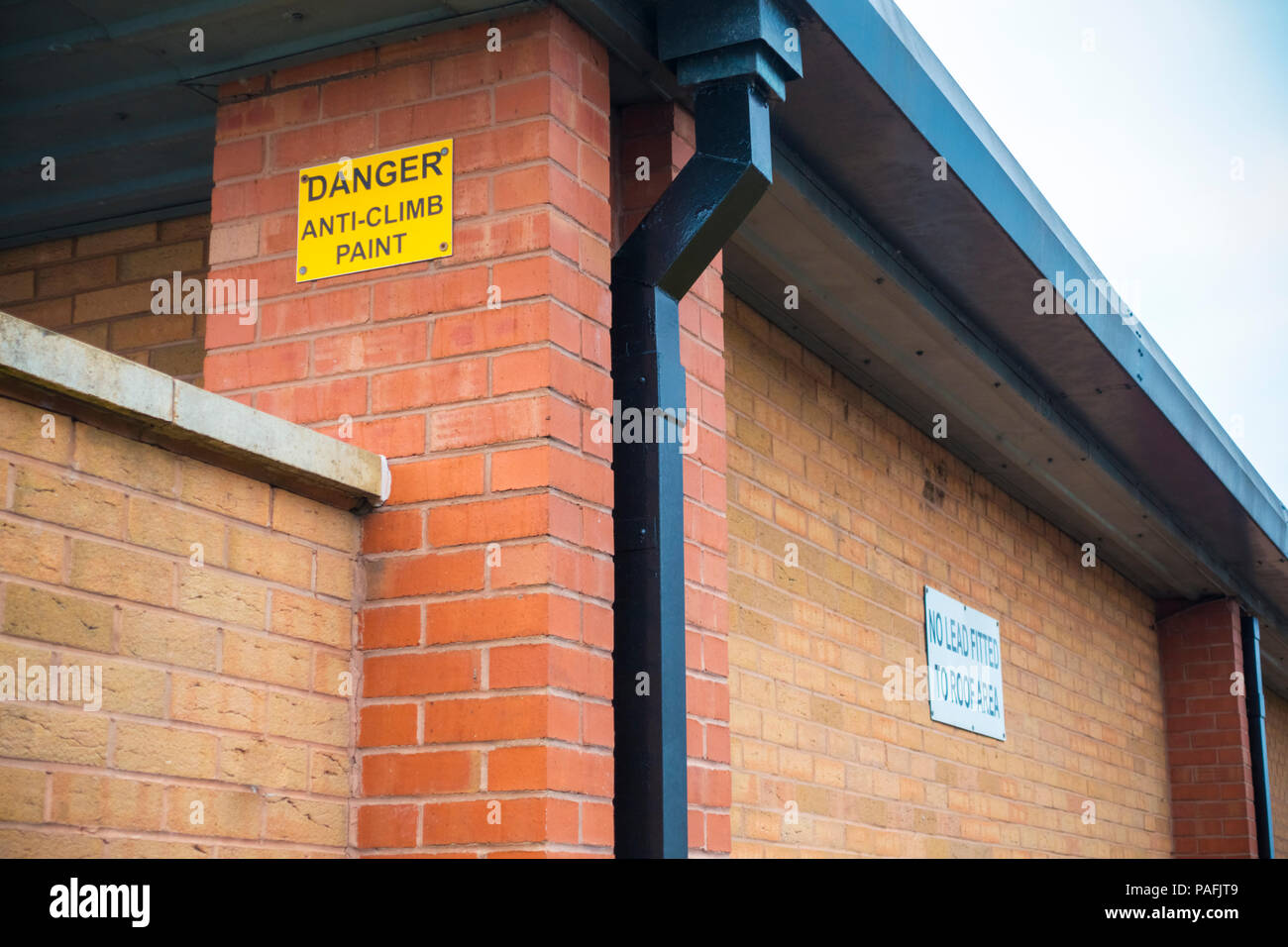 Signs on a building warning about no lead fitted to roof, and anti ...