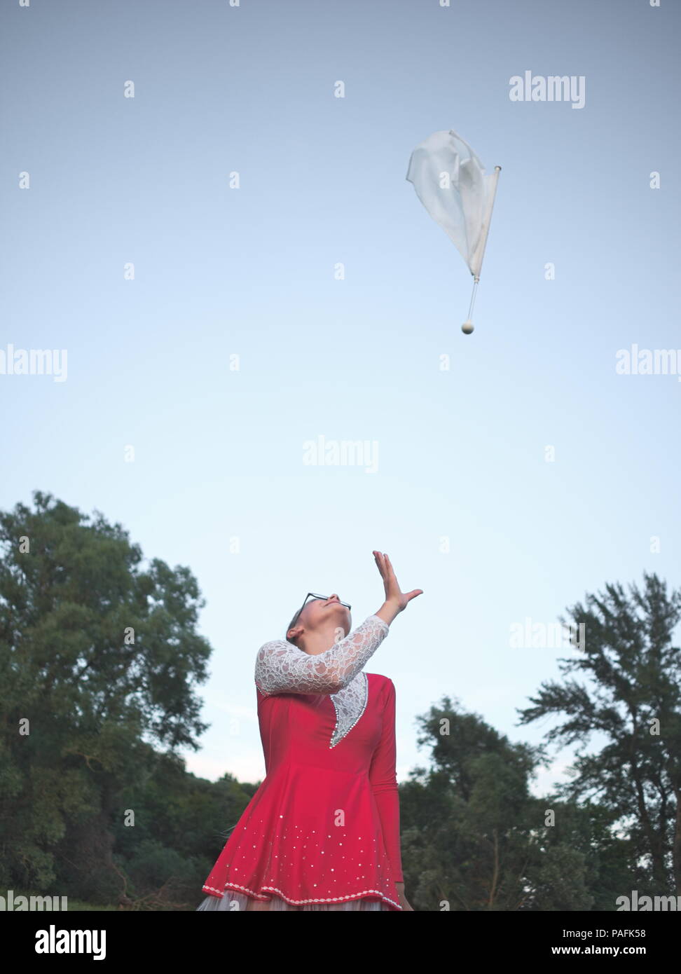 Bespectacled Blonde Teen Majorette Girl with White Flag Outdoors in Red ...