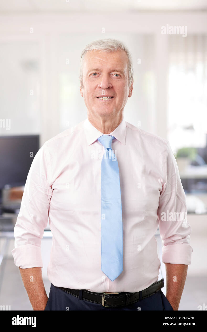 A senior sales manager standing at the office while looking at camera ...