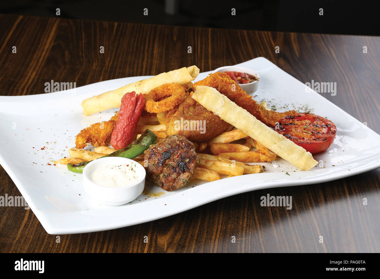 Mixed appetizer of french fries, fried sasusage, fried zucchini, pastry ...