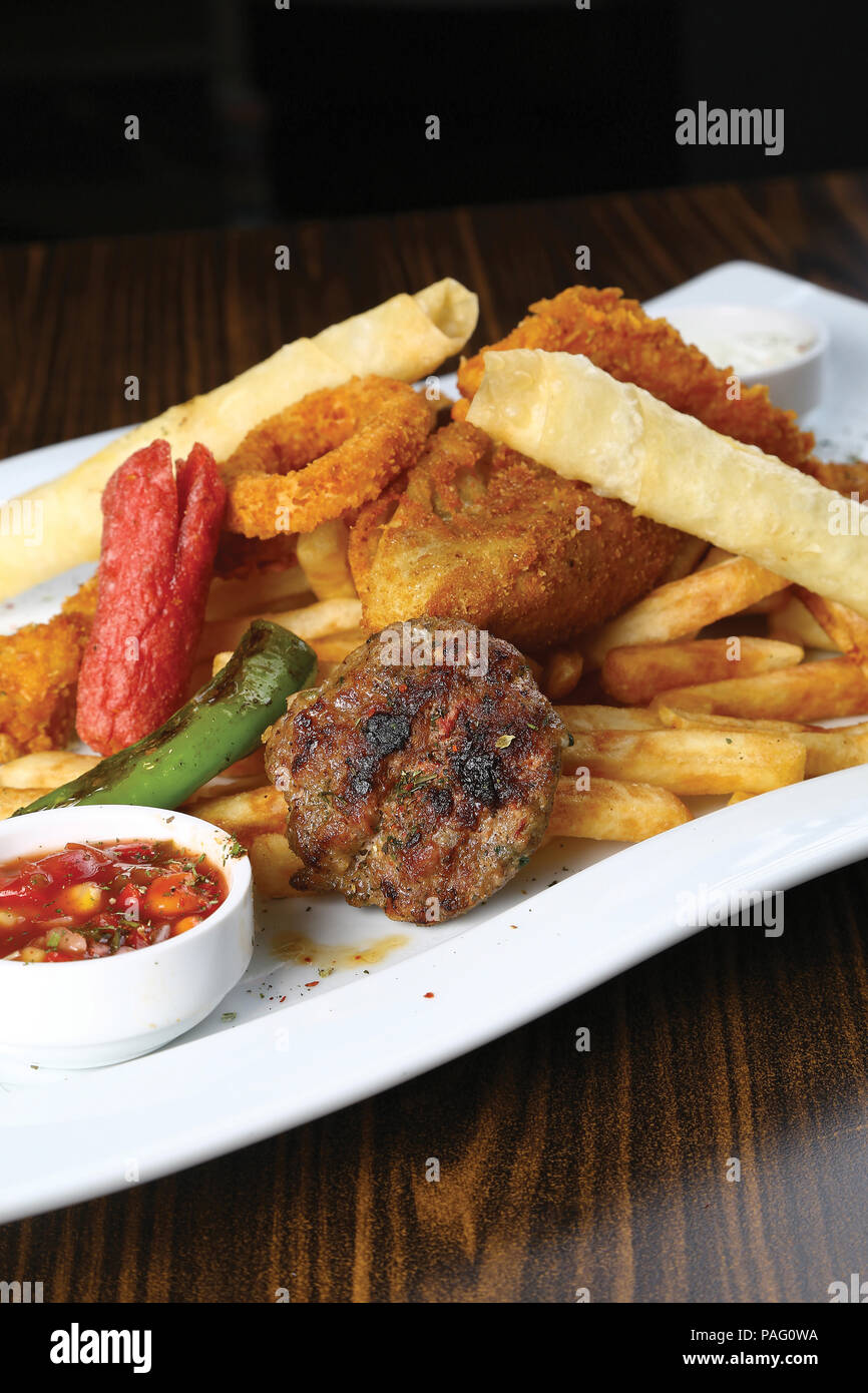 Mixed appetizer of french fries, fried sasusage, fried zucchini, pastry ...