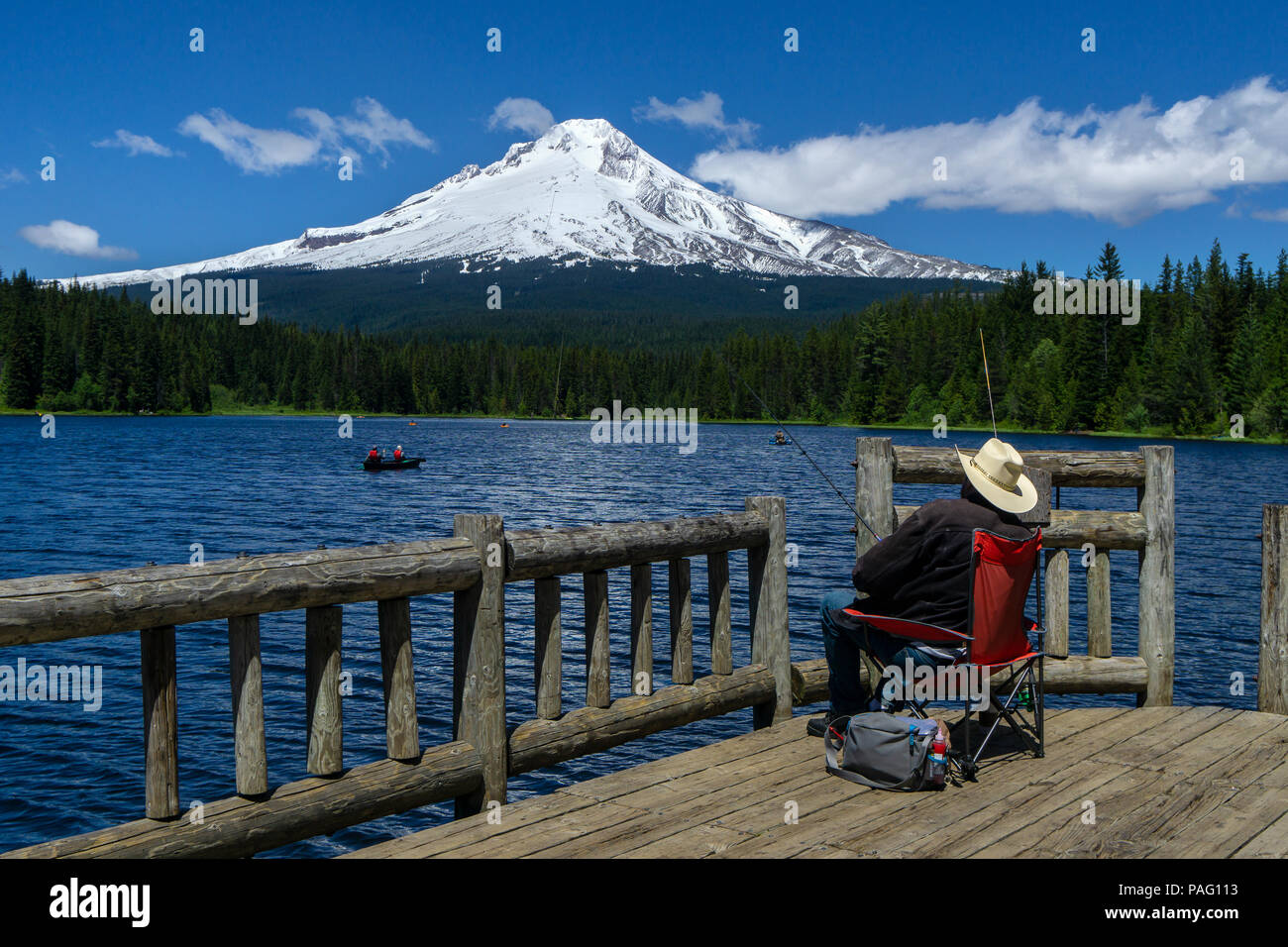 Old fisherman fishing from a wooden boardwalk at Trillium Lake with the ...