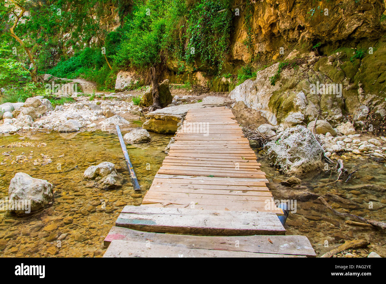 An old wooden bridge over the river at Nidri area with the waterfalls ...