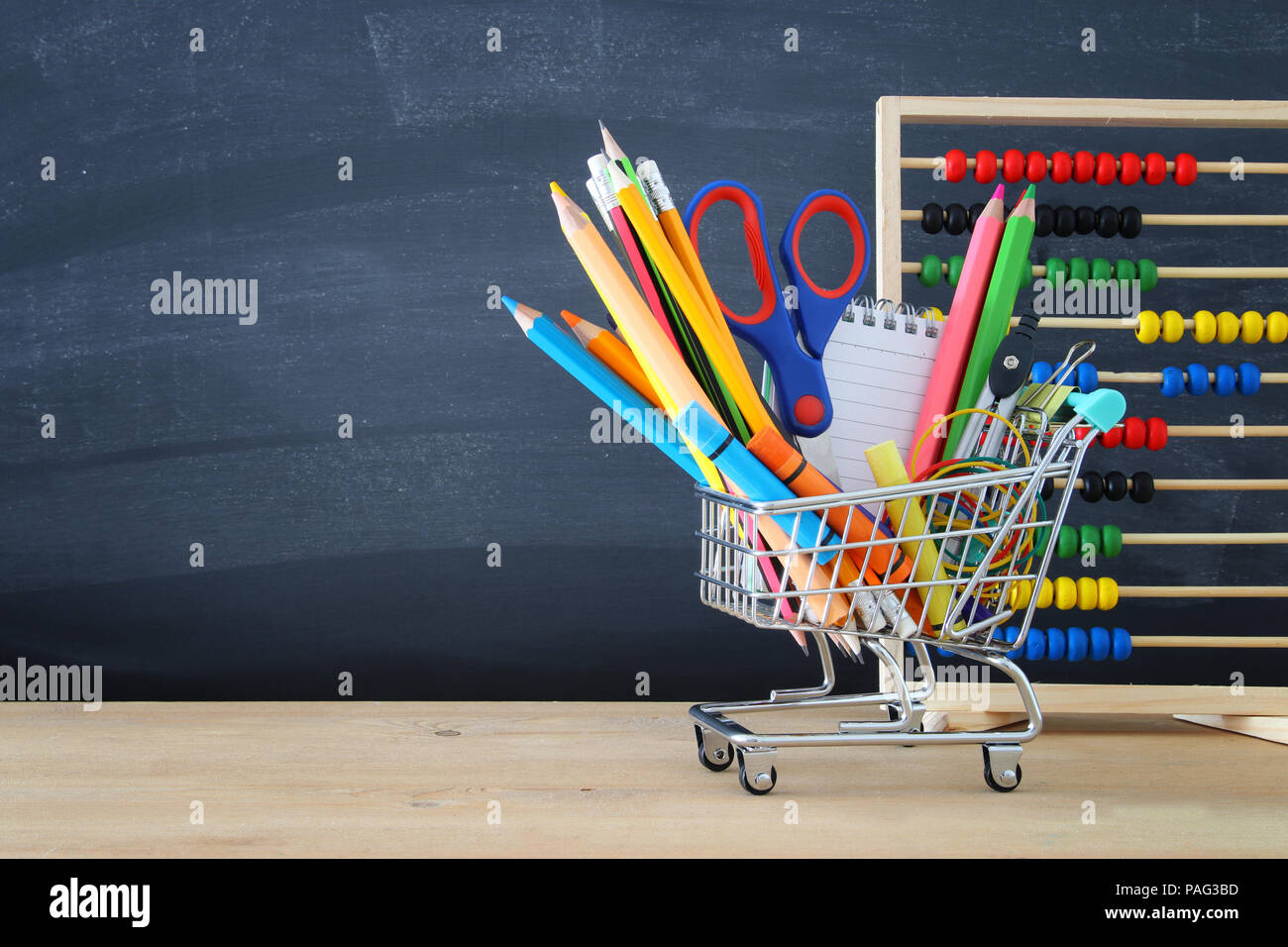 Shopping cart with school supply in front of blackboard. Back to school ...