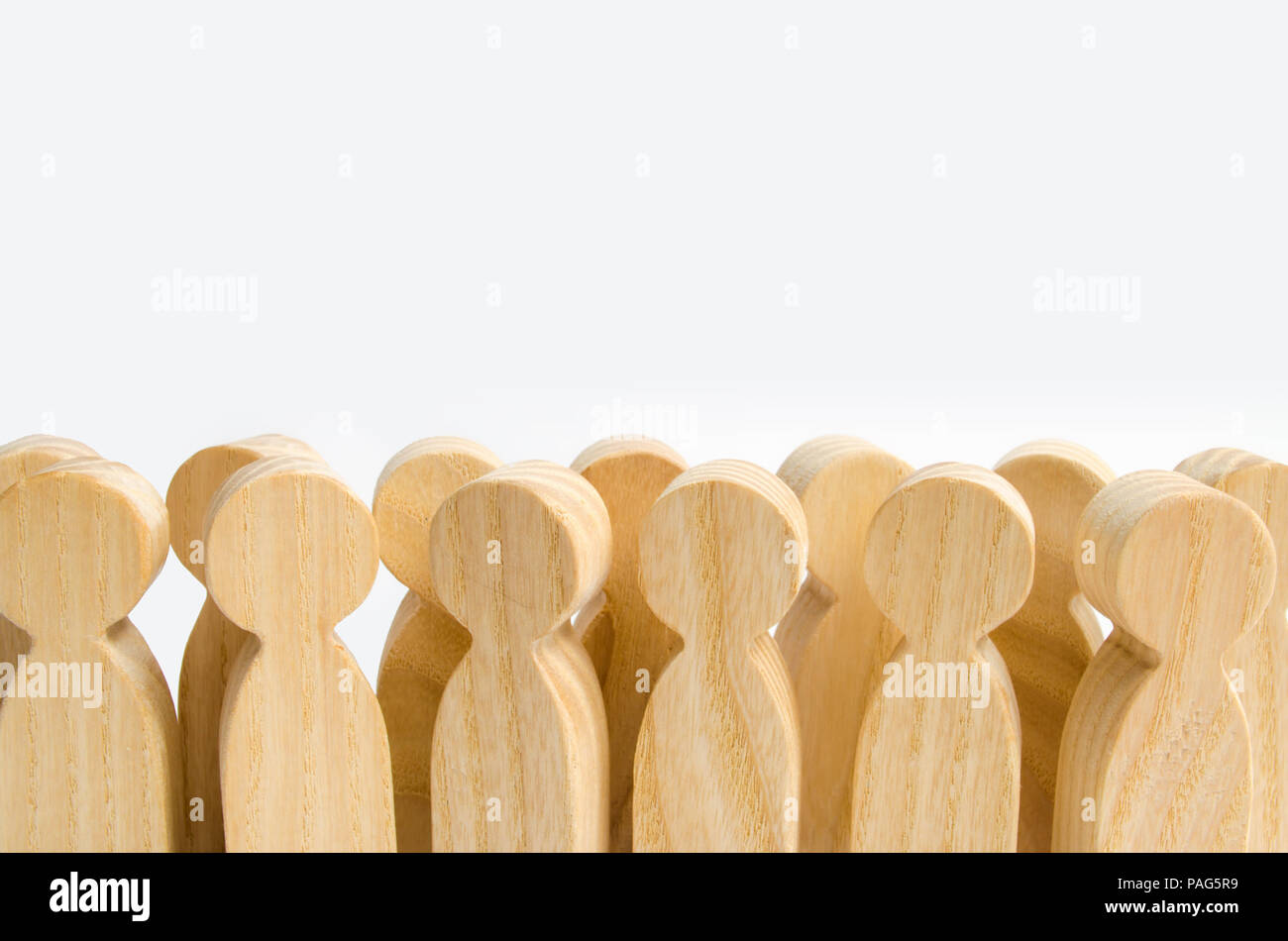 A crowd of wooden figures of people standing on a white background. The ...
