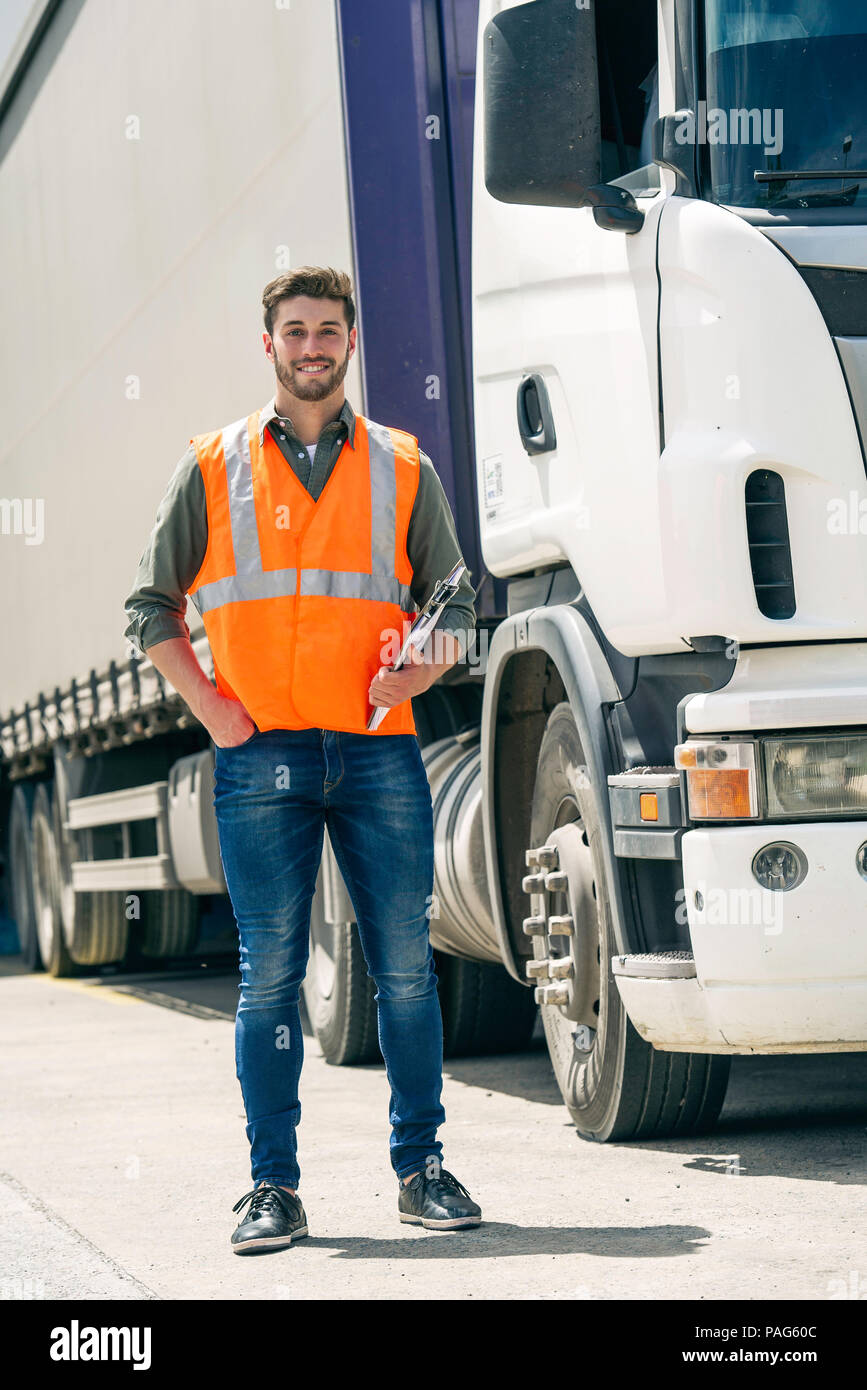 Worker standing in front of lorry Stock Photo - Alamy
