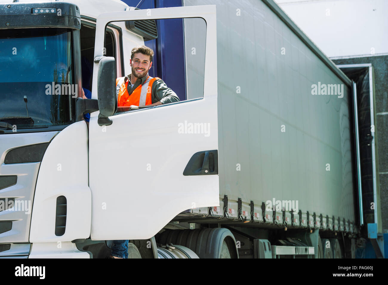 Worker standing by lorry door Stock Photo - Alamy