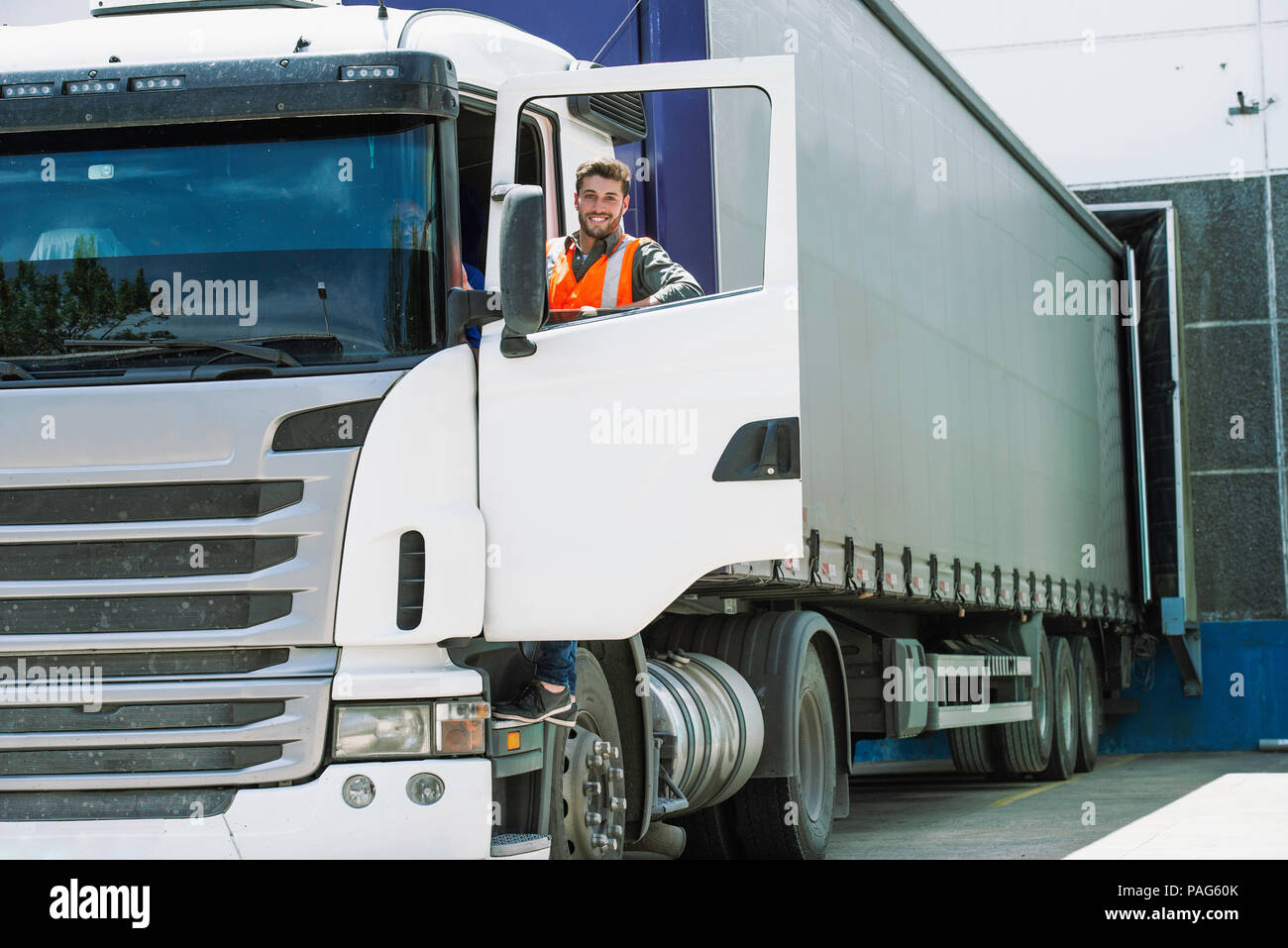 Worker standing by lorry door Stock Photo - Alamy