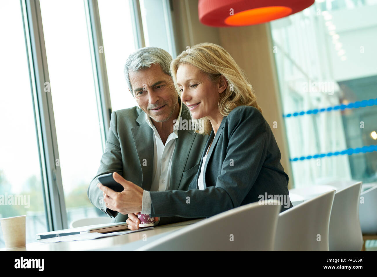 Businesspeople using smart phone in cafeteria Stock Photo - Alamy