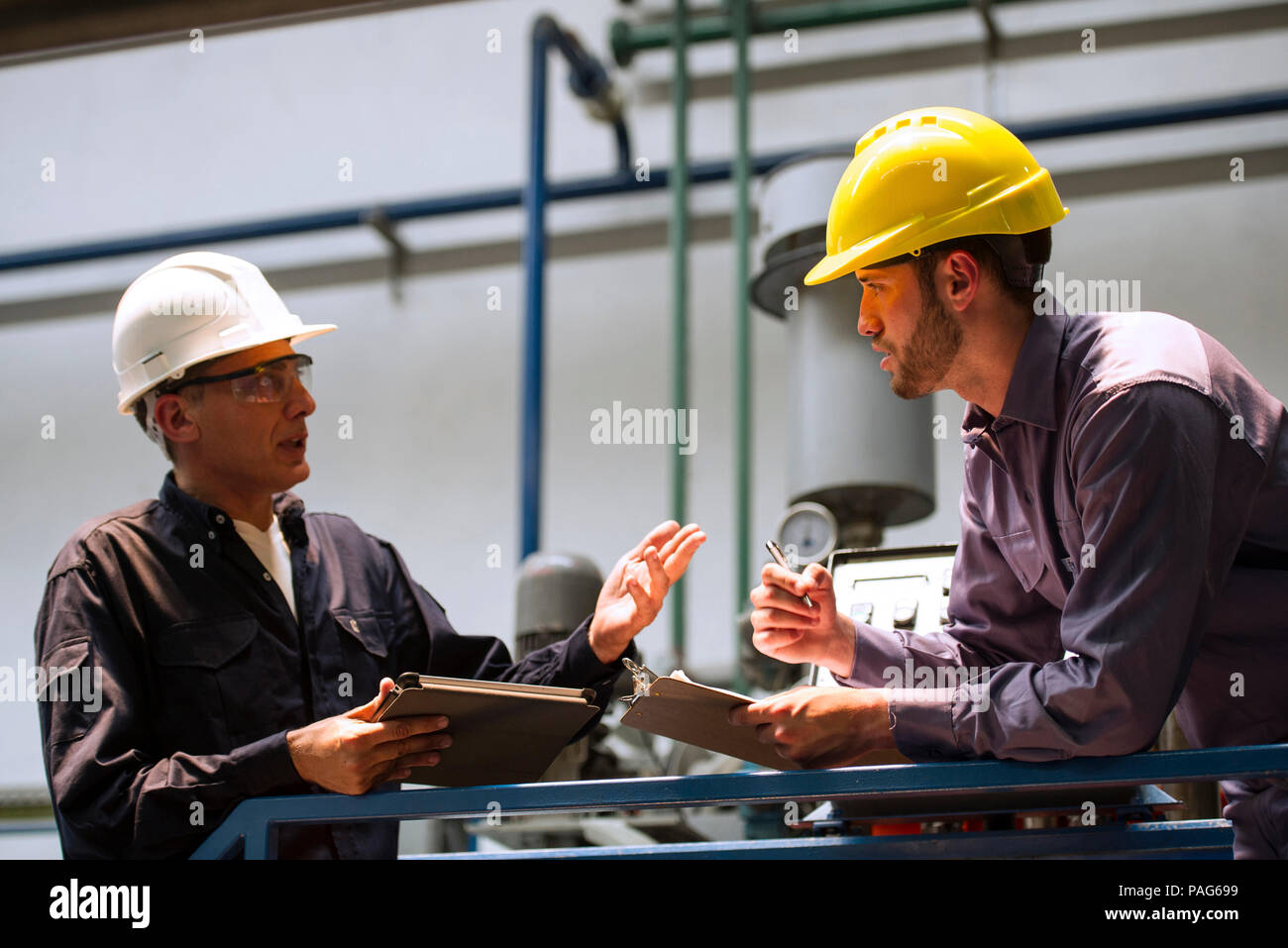 Factory workers discussing with each other in factory Stock Photo - Alamy