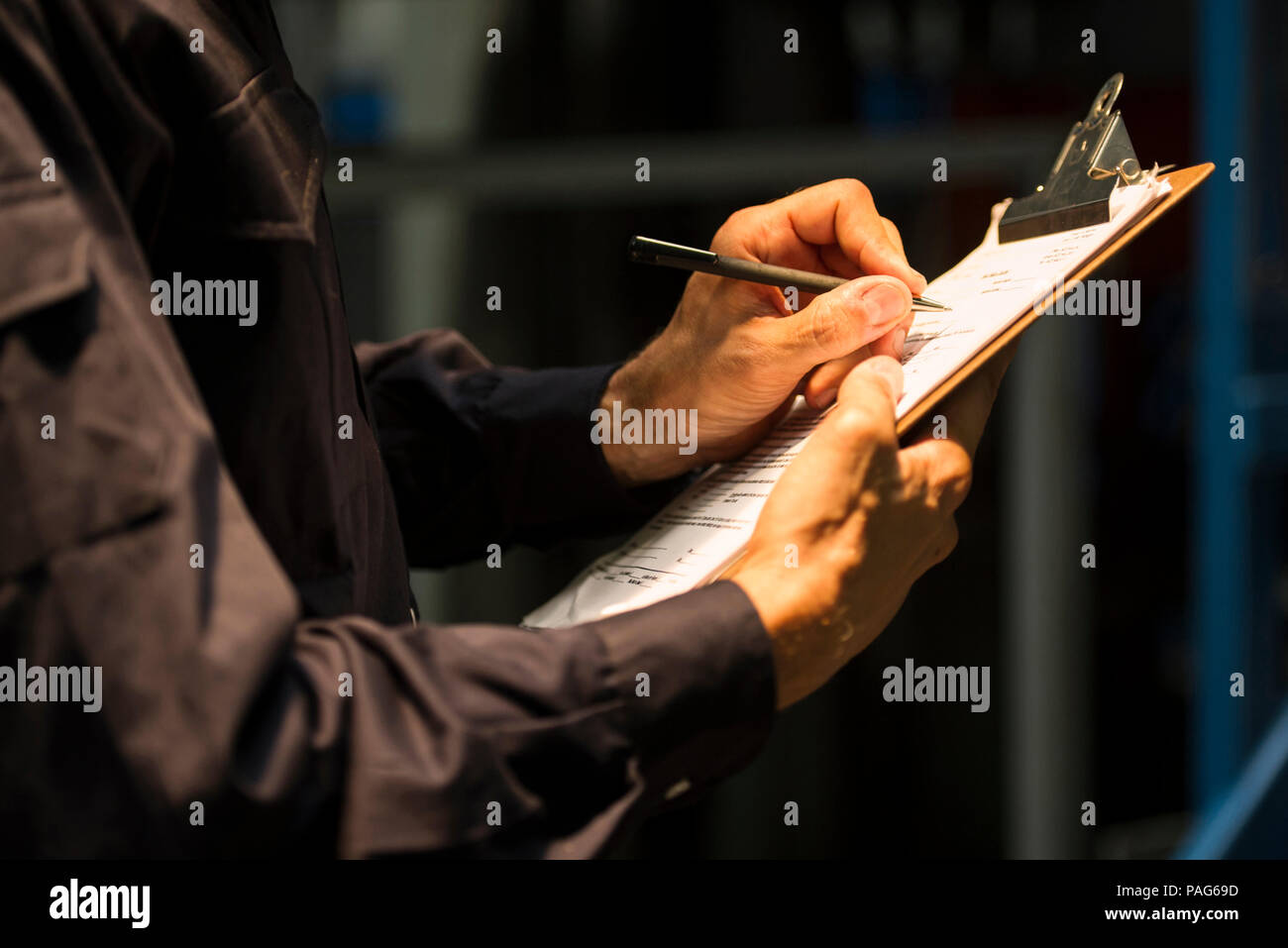 Factory worker writing on clipboard Stock Photo - Alamy