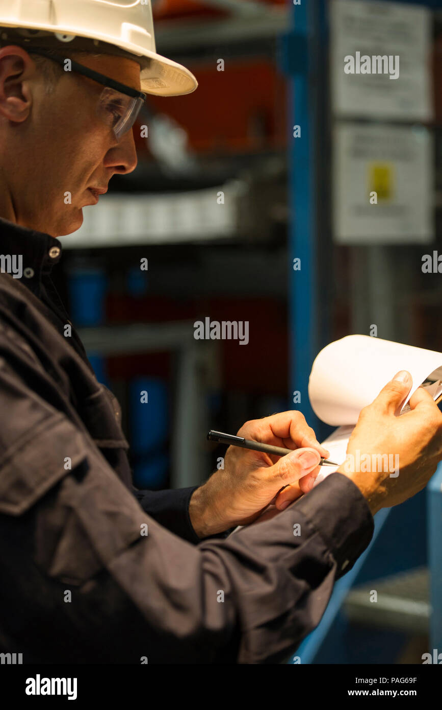Factory working writing on clipboard Stock Photo - Alamy