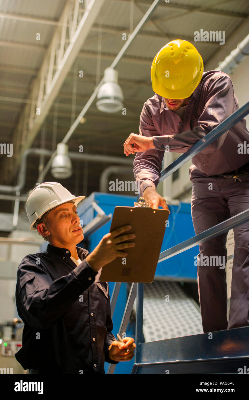 Factory workers with clipboard in factory Stock Photo - Alamy