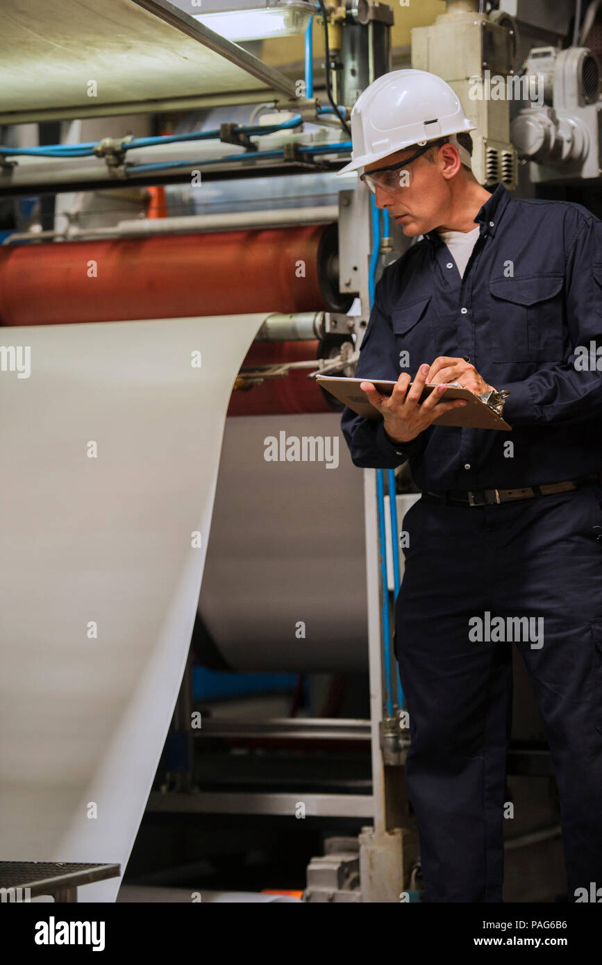 Factory worker writing on clipboard in factory Stock Photo - Alamy
