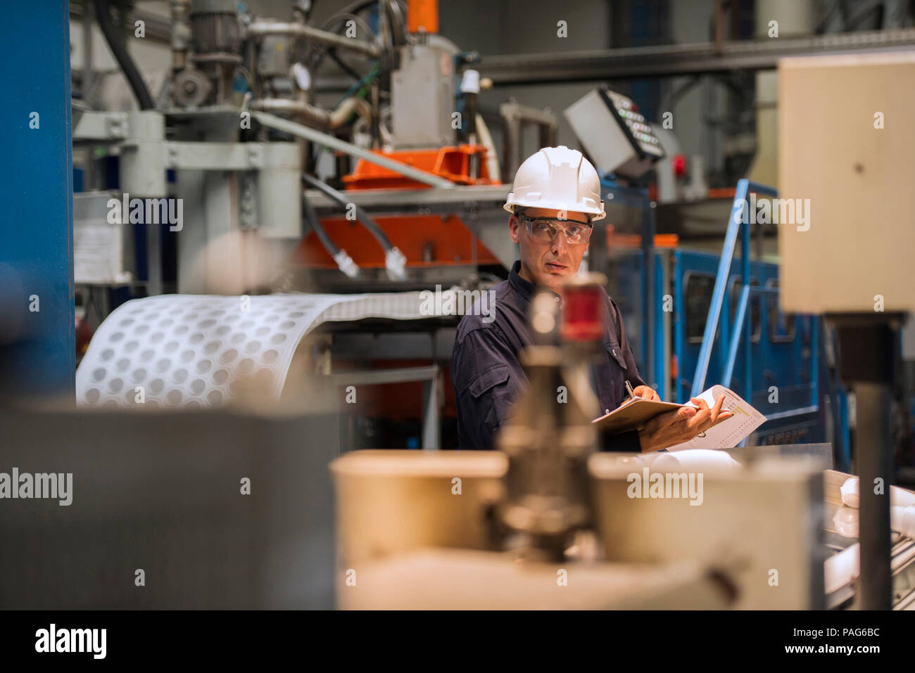 Factory worker with clipboard in factory Stock Photo - Alamy