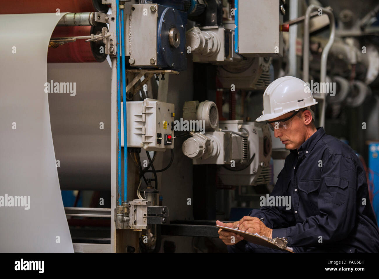Factory worker writing on clipboard in factory Stock Photo - Alamy