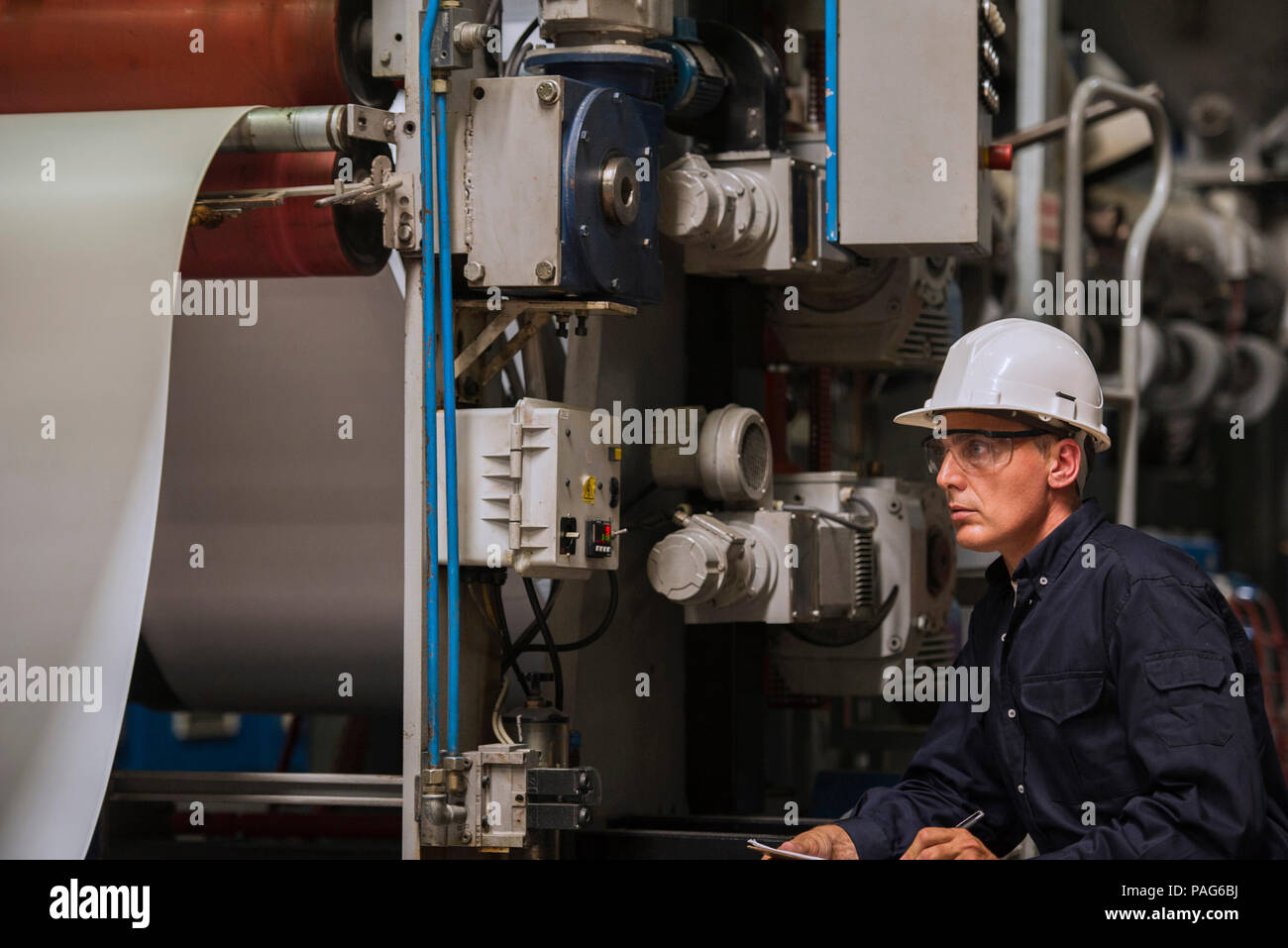 Factory worker writing on clipboard in factory Stock Photo - Alamy