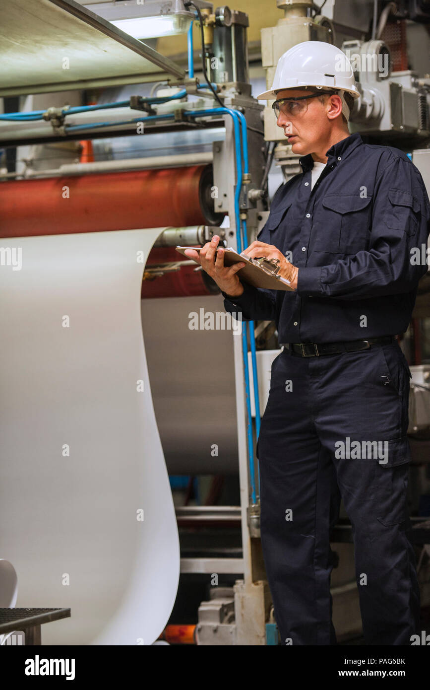 Factory worker writing on clipboard in factory Stock Photo - Alamy