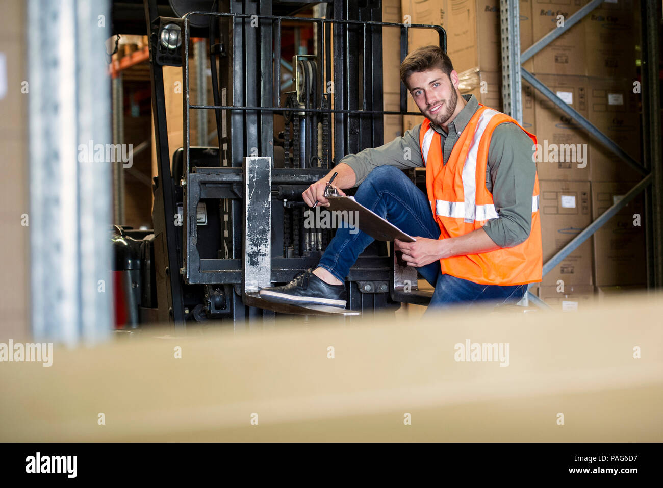 Worker sitting with clipboard in warehouse Stock Photo - Alamy
