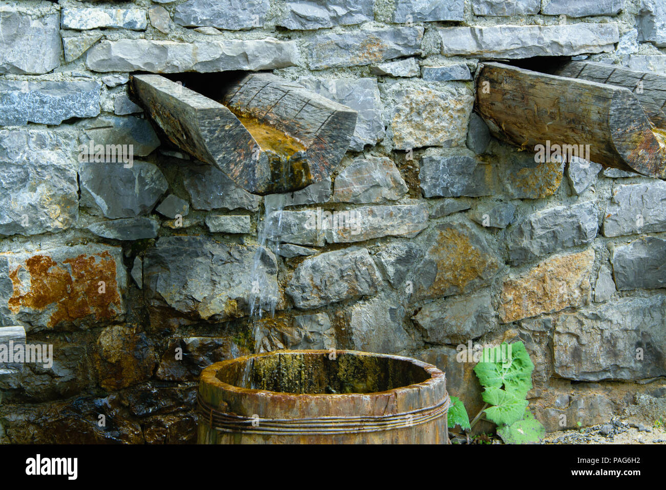 Traditional rustic handmade fountain in the mountain, where flows ...