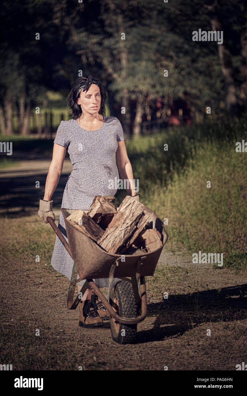 A pregnant woman in a vintage dress and work boots pushing a ...