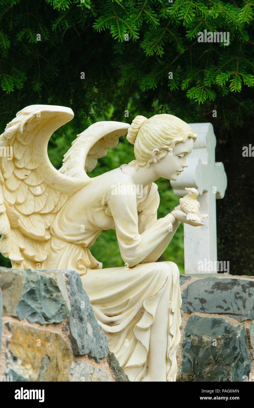 Marble sculpture of female angel sitting on the rock and holding a bird ...