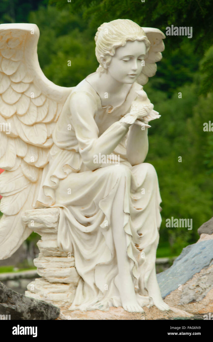 Marble sculpture of female angel sitting on the rock and holding a bird ...
