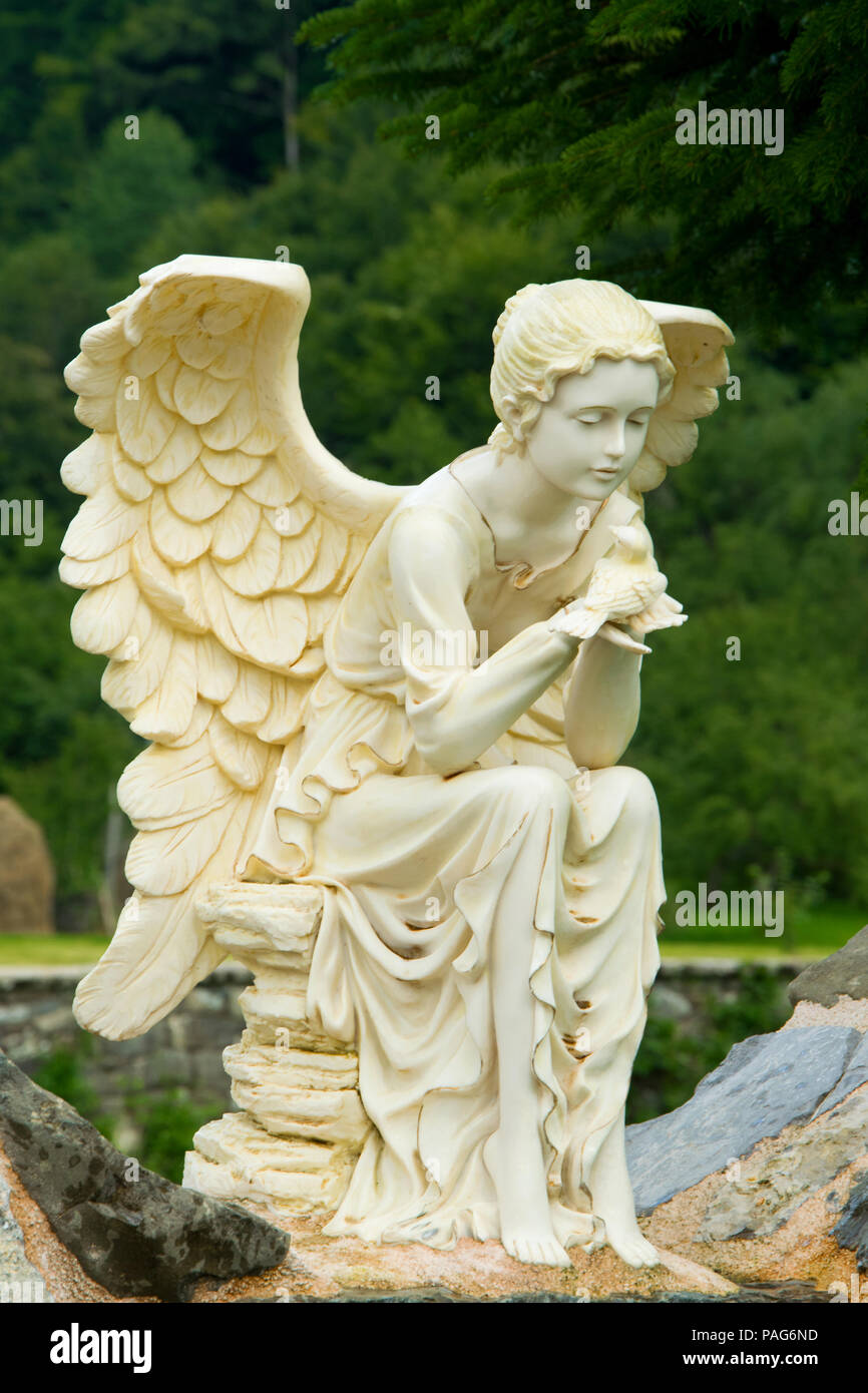 Marble sculpture of female angel sitting on the rock and holding a bird ...