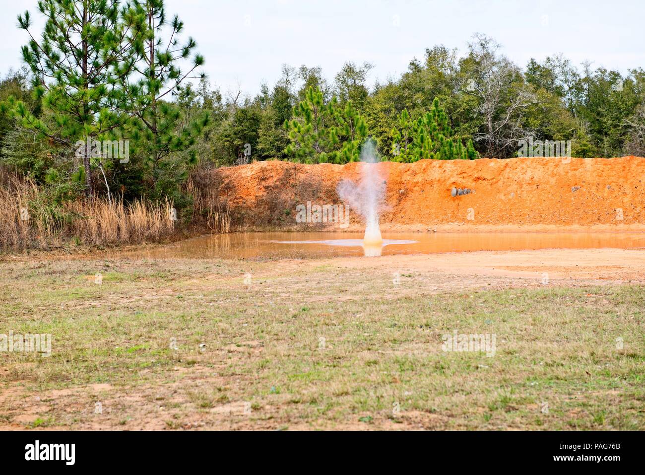 Water splashes in large red clay puddle Stock Photo - Alamy