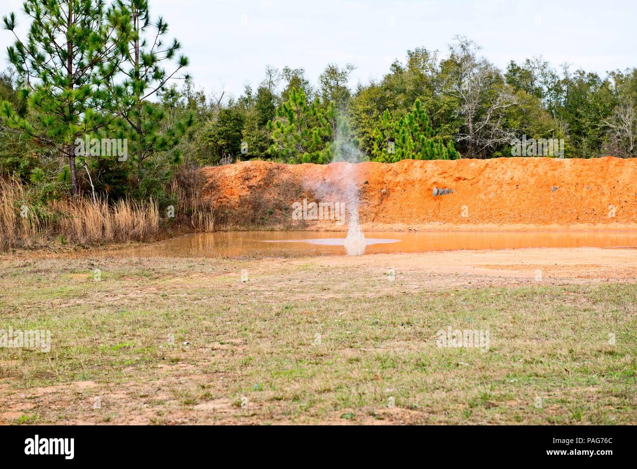 Water splashes in large red clay puddle Stock Photo - Alamy